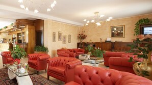Uma sala de estar ampla com sofás de couro vermelho, uma mesa de centro e um espaço de bar com televisão.