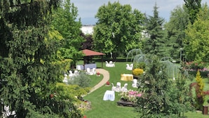 Um jardim bem cuidado com um caminho bem definido, mobiliário de exterior arrumado e um gazebo.