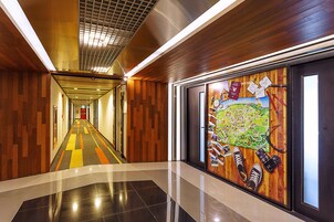 Um corredor com painéis de madeira, piso de azulejos e um grande mural na parede.