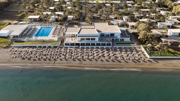 Vista aérea de um resort com uma piscina grande, vários edifícios e uma área de praia.