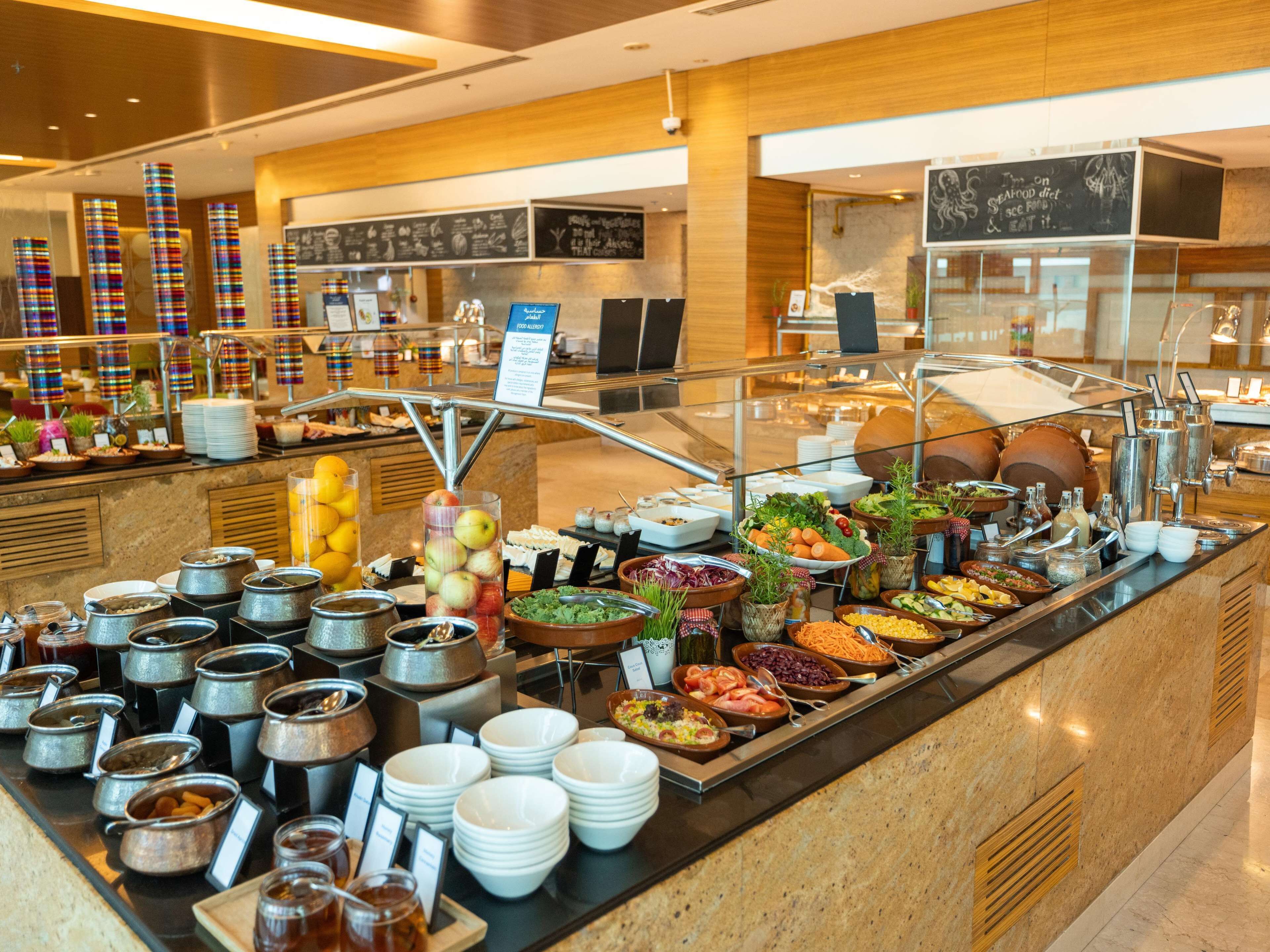 Buffet com diversas opções de comida, incluindo frutas, legumes e pratos prontos.
