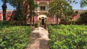 Uma passagem leva a um edifício com fachada vermelha e entrada em arco.