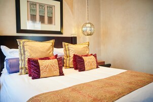 Cama bem arrumada com almofadas estampadas e manta decorativa.