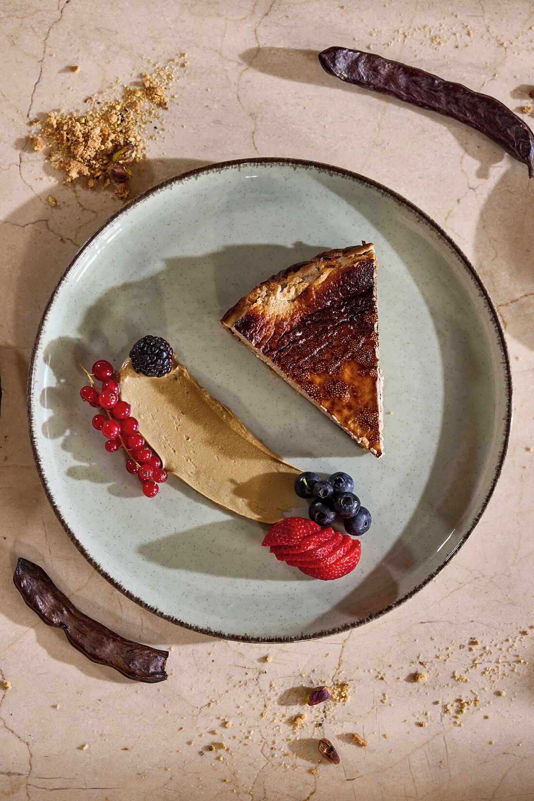 Um prato com uma fatia de torta, frutas vermelhas e uma porção de fruta em uma superfície com textura.