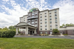 Um hotel com entrada central, vários andares e estacionamento.