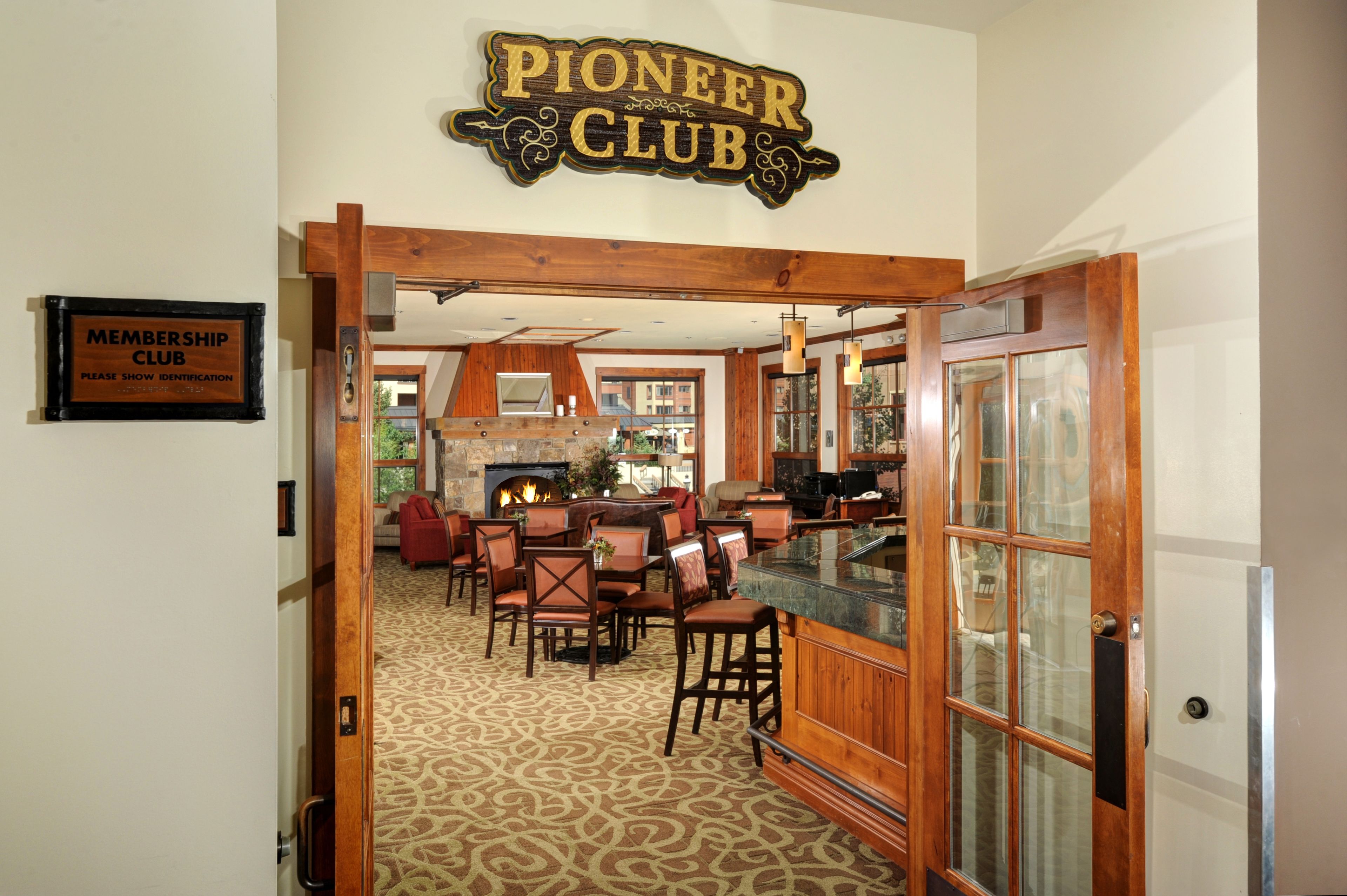 Um clube Pioneer com placa de sócios, área de bar e lareira.