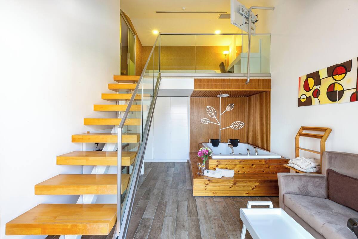 Um interior moderno com escada de madeira, guarda-corrimão de vidro, parede de madeira com design de folha, um sofá e um quadro na parede.