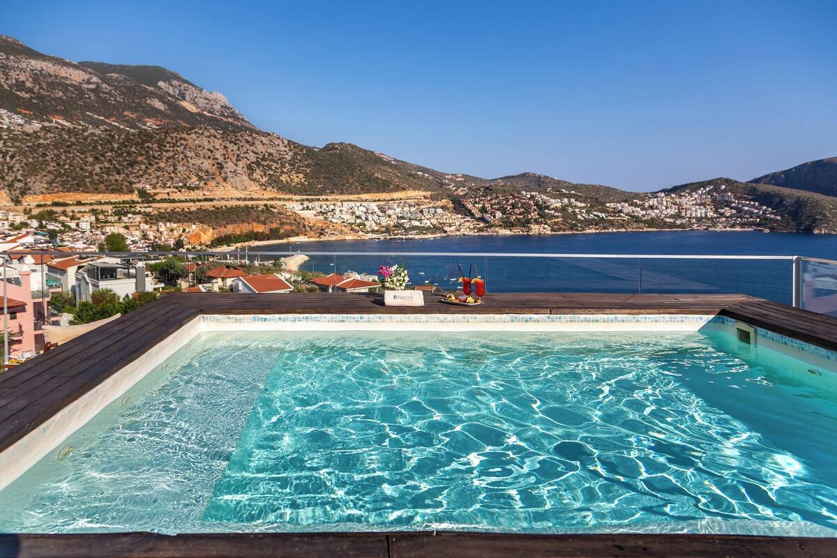 Piscina com vista para uma cidade costeira e montanhas.