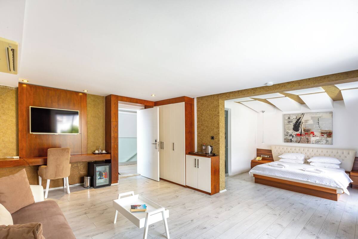 Quarto moderno com cama, televisão, escrivaninha e cadeira.