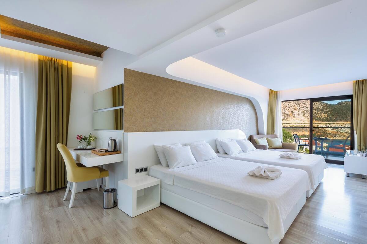 Quarto de hotel moderno com uma cama grande, uma escrivaninha e vista para o exterior.
