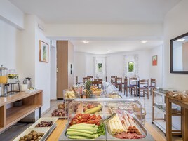 Buffet com diversas opções de comida e área de estar com mesas e cadeiras.