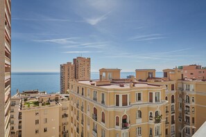 Um edifício alto com várias varandas, vista clara do mar e céu ensolarado.