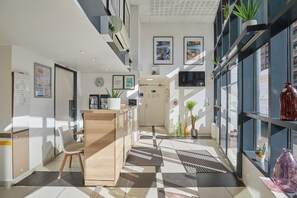 Um hall de hotel moderno com balcão de recepção, área de estar e plantas decorativas.