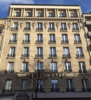 Um edifício de vários andares com uma placa na entrada que diz 'Grand Hotel'.