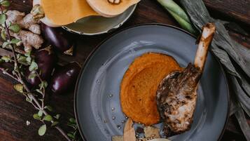 Um prato com carne grelhada, um purê de laranja cremoso e alguns temperos.