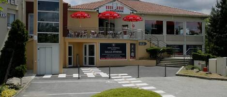 Hotel com terraço, área de estar ao ar livre e placa com 'SALLE ATHENA'.