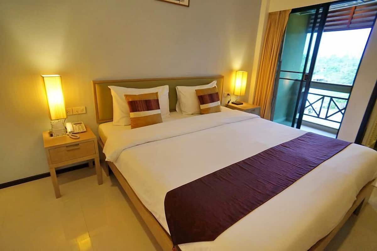 Quarto de hotel com uma cama grande, duas mesas de cabeceira e uma janela com vista.