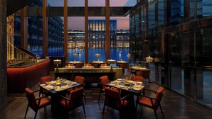 Um restaurante moderno com vista para um edifício à beira da água.