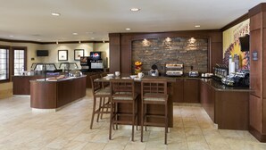 Cozinha ampla e bem iluminada, com painel de parede em pedra, um espaço para café e um buffet.