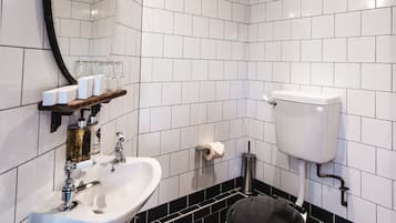 Um banheiro moderno com azulejos brancos, vaso sanitário preto, pia e espelho.