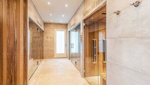 Corredor moderno de hotel com portas de vidro, painéis de madeira e piso ladrilhado.