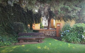 Um banco num jardim com um muro de pedra e uma árvore.