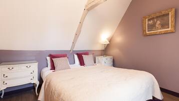 Quarto com cama, cômoda branca e mesa de cabeceira com abajur.