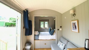 Um quarto acolhedor com uma cama, uma janela, um sofá e um quadro na parede.