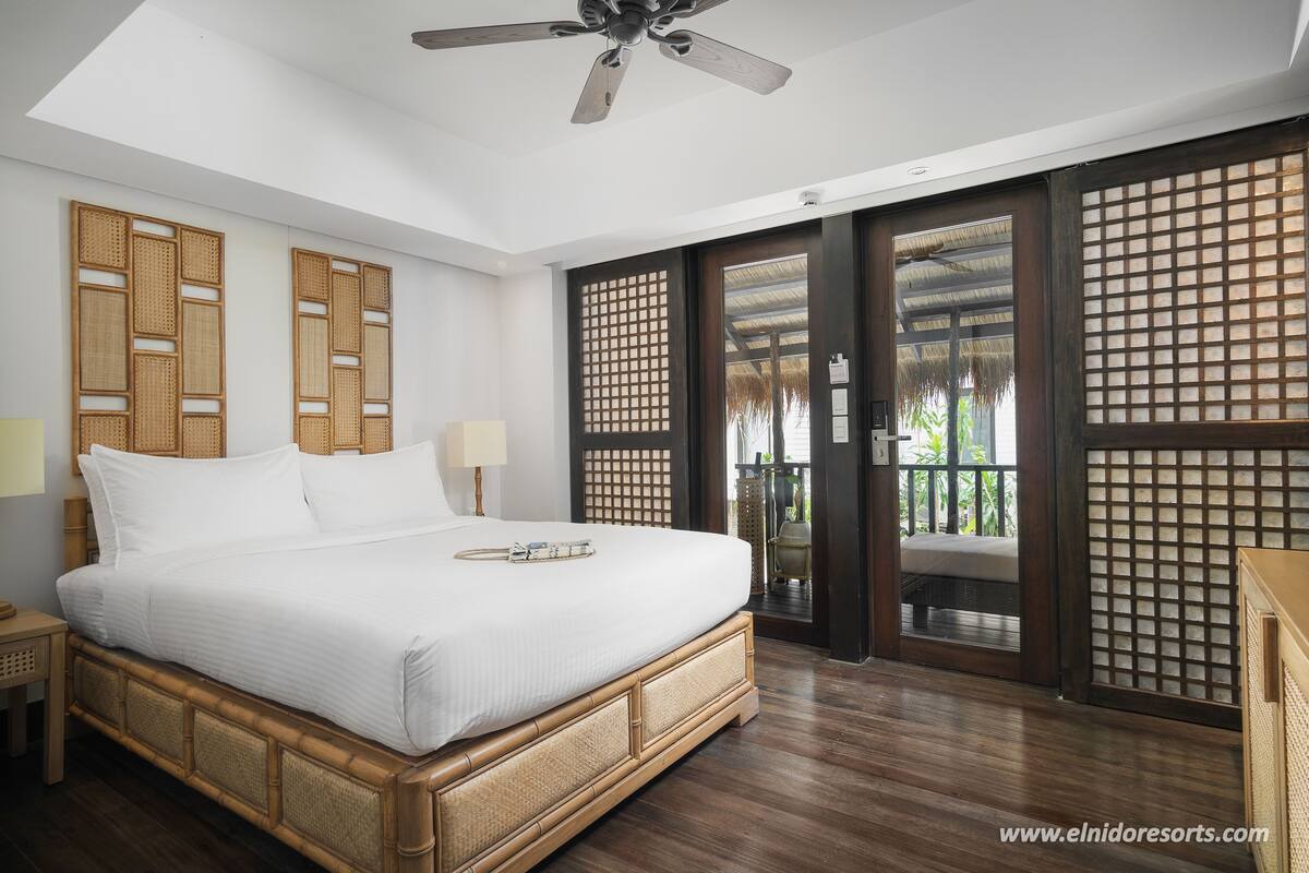 Um quarto espaçoso com uma cama grande, cabeceira de madeira e ventoinha no teto.