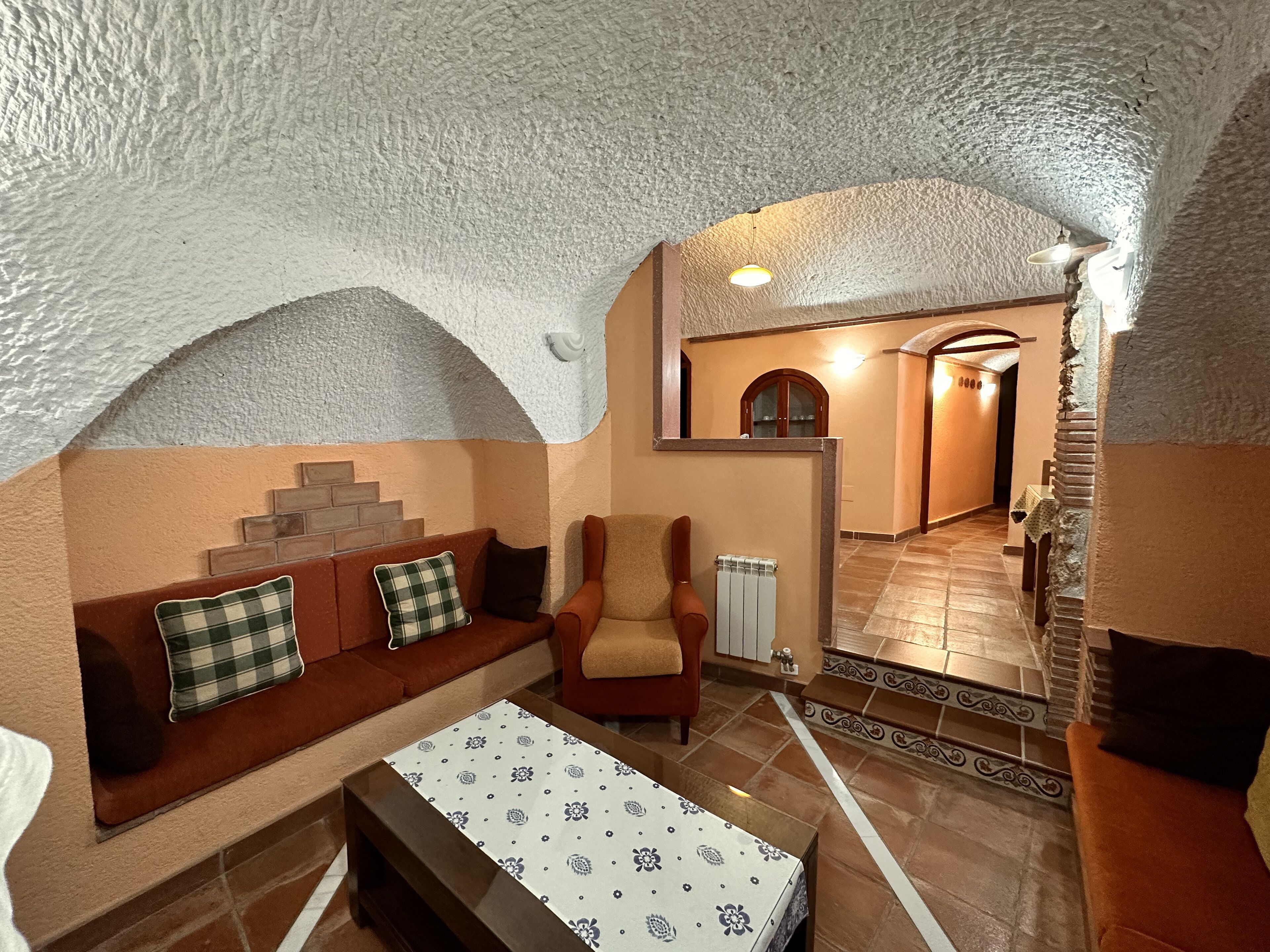 Uma sala de estar acolhedora com sofá, poltrona e uma mesinha. Uma escada leva a outro cômodo.