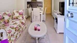 Um espaço de estar compacto com sofá, mesa redonda pequena, área de refeições e televisão.