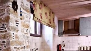 Uma cozinha com paredes de pedra, uma pia, armários e um fogão.