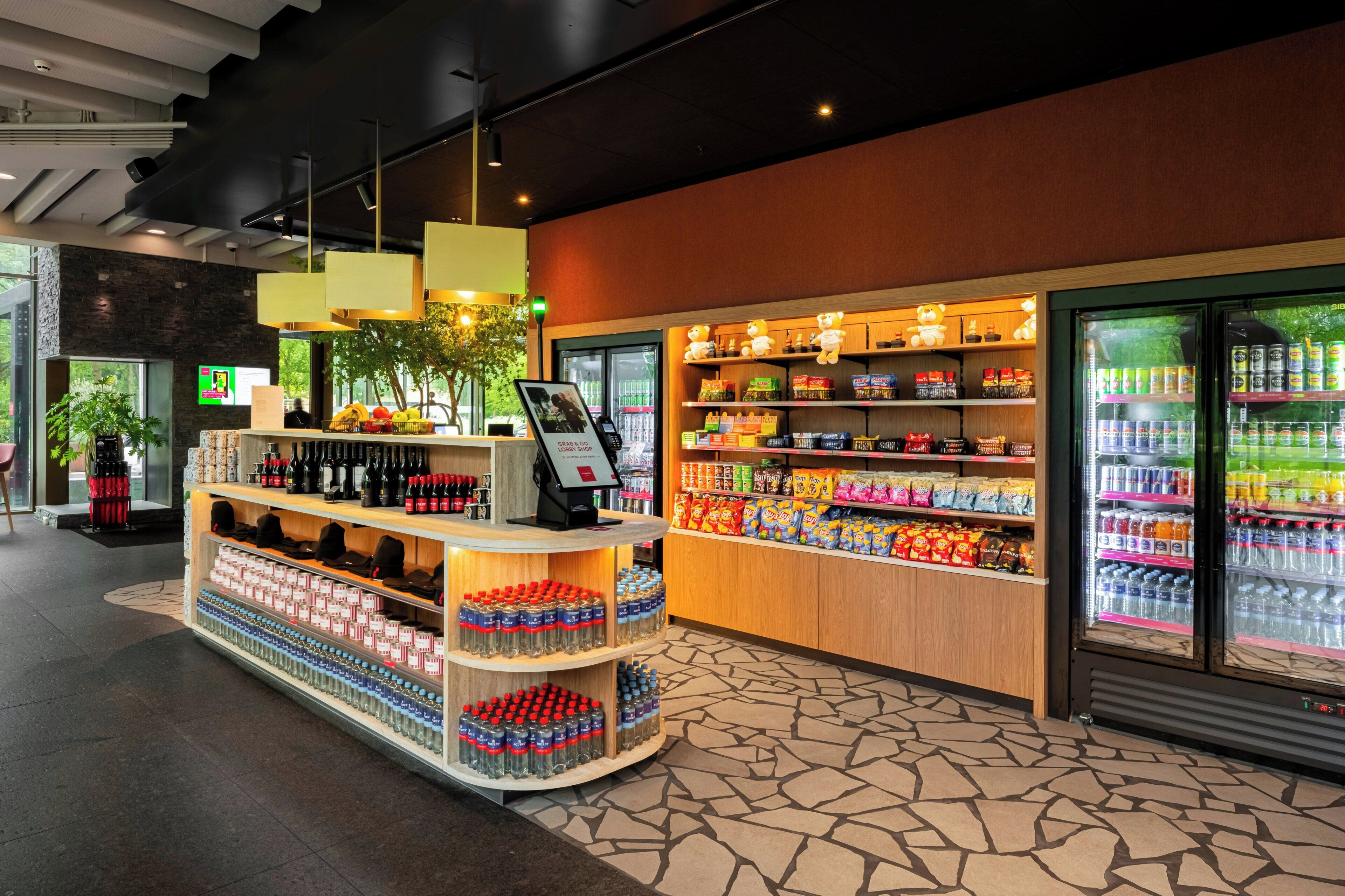 Uma área comercial moderna com resfriador de vinhos, prateleiras para lanches e um dispensador de bebidas.