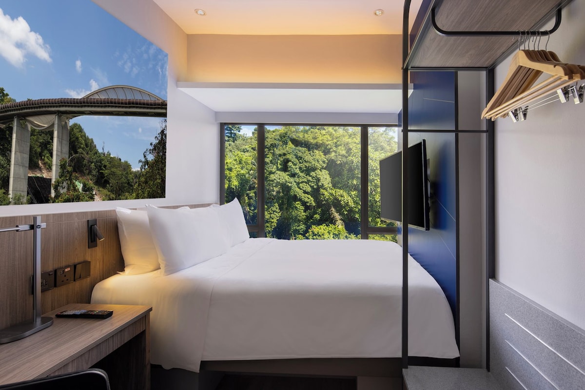 Quarto de hotel moderno com uma cama grande, uma escrivaninha e uma televisão.