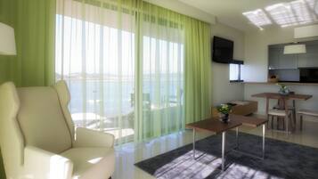 Quarto de hotel moderno com varanda, televisão de tela plana, área de jantar e um sofá.