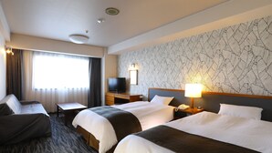 Quarto de hotel com duas camas, uma escrivaninha, uma televisão e papel de parede estampado.