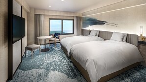 Quarto de hotel com uma cama grande, televisão, mesa pequena e janela com vista.