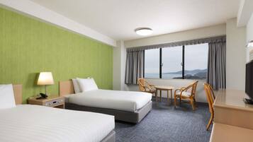 Quarto de hotel com duas camas, uma escrivaninha, televisão e vista para o exterior.