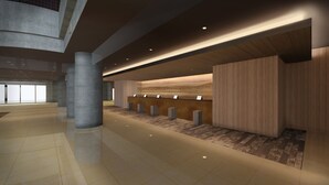 Um hall amplo com balcão de recepção, colunas e piso lustroso.