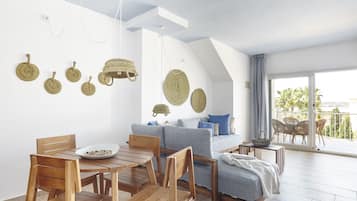 Uma sala moderna com área de jantar, sofá e varanda com mobiliário para exterior.