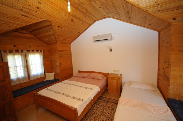 Quarto de cabana de madeira com cama, um banco e uma pequena mesa de cabeceira.