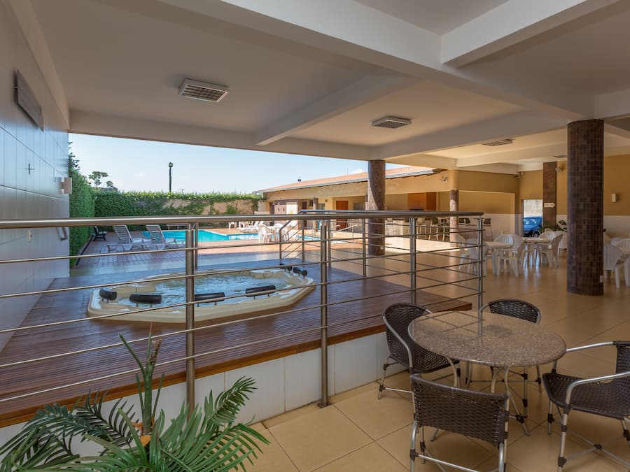 Terraço no telhado com banheira de hidromassagem, área de estar ao ar livre e vista para a piscina e um edifício.