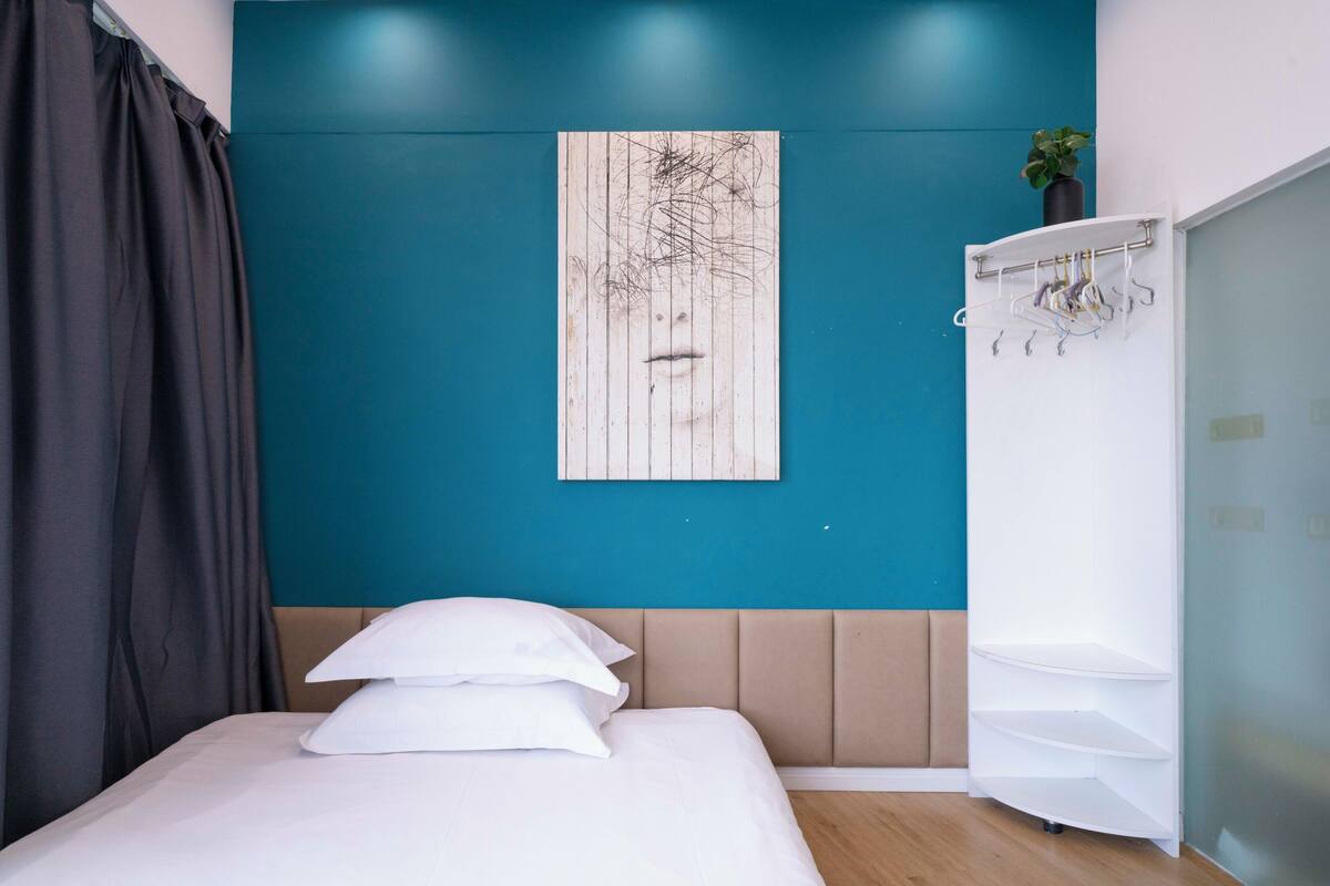 Quarto com cama, uma obra de arte na parede, guarda-roupa e uma planta.
