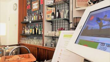 Uma área de bar com prateleiras cheias de garrafas e copos, um relógio e um quadro de cardápio.