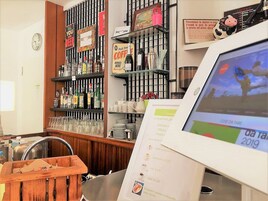 Uma área de bar com prateleiras cheias de garrafas e copos, um relógio e um quadro de cardápio.