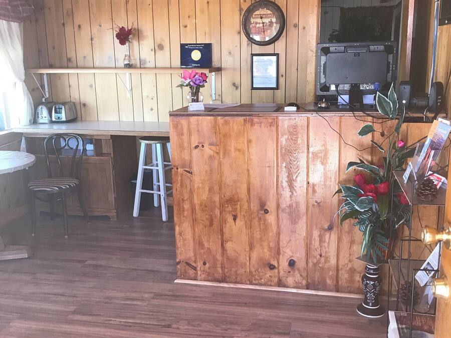 Interior em madeira com área de bar, televisão e um pequeno espaço de estar com uma cadeira e um banquinho.