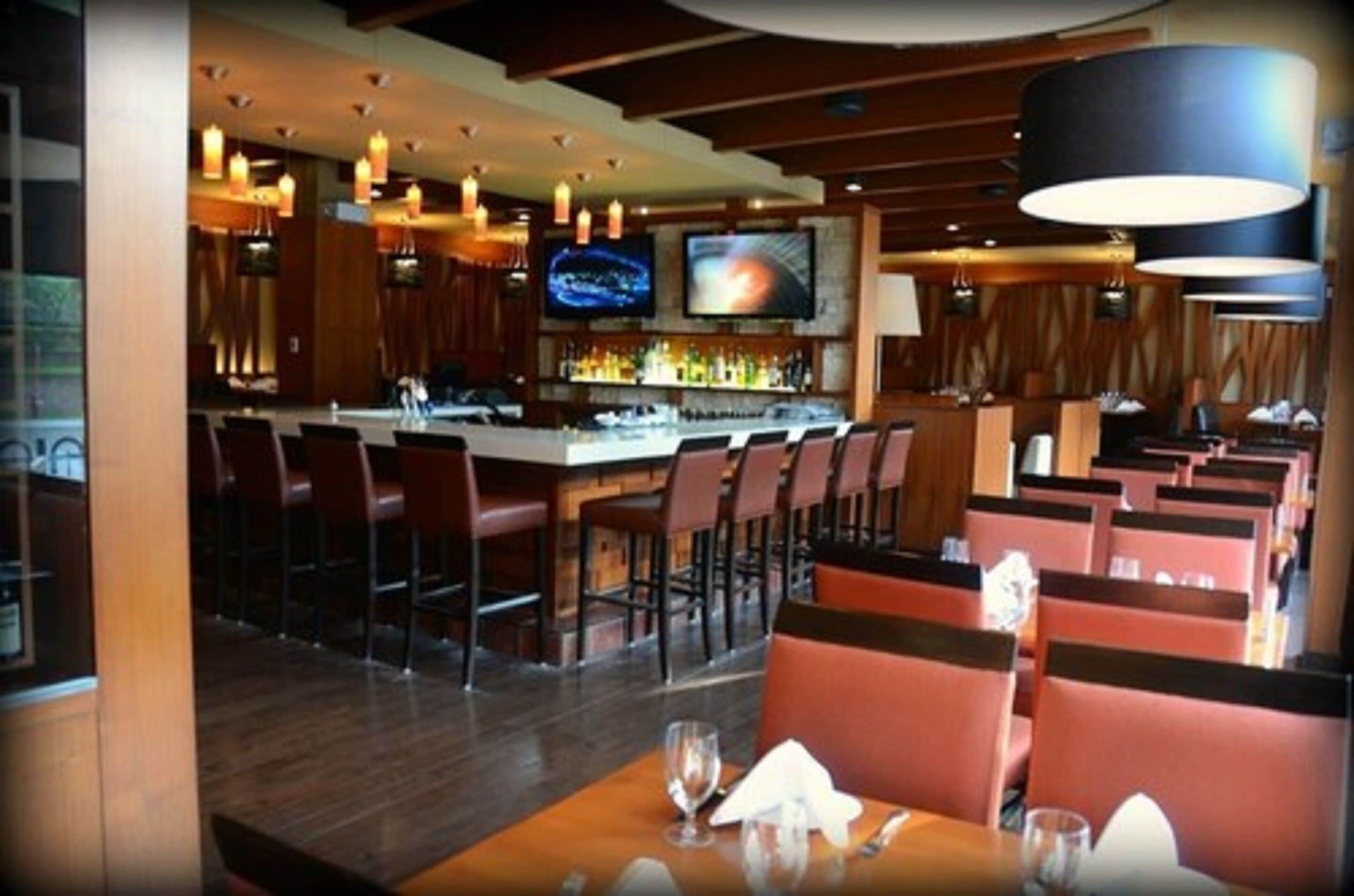 Um restaurante com área de bar, cabines e uma televisão.