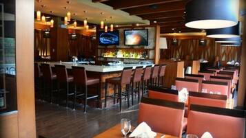 Um restaurante com área de bar, cabines e uma televisão.