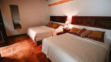 Quarto com duas camas, mesa de cabeceira com abajur, cabeceira de madeira e espelho na parede.