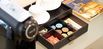Máquina de café e gaveta com saquinhos de chá e cápsulas de café.